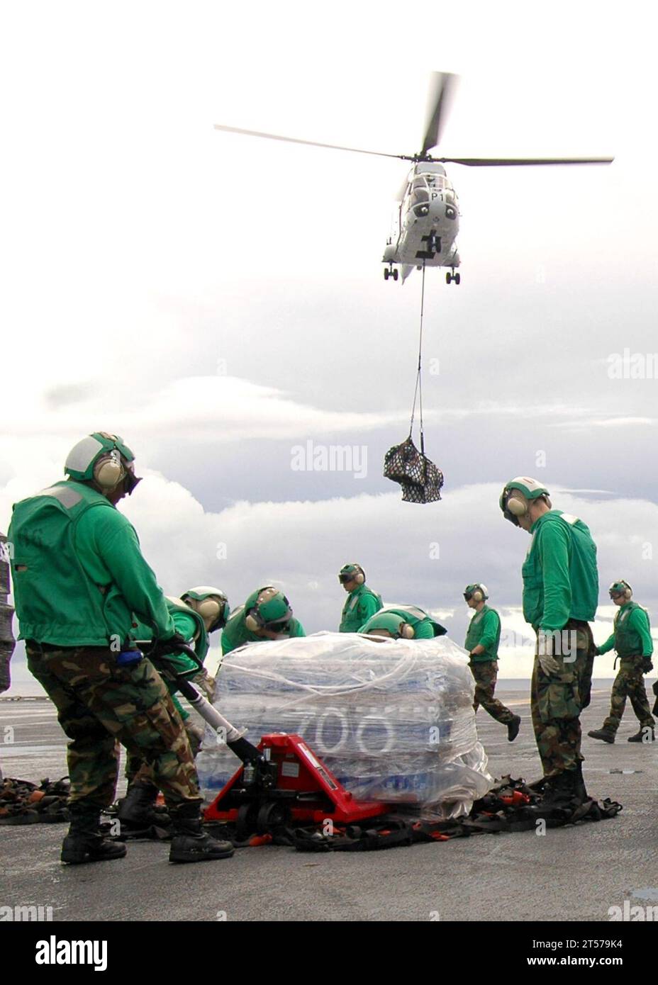 US Navy Sailors move cargo on the flight deck of the aircraft carrier ...