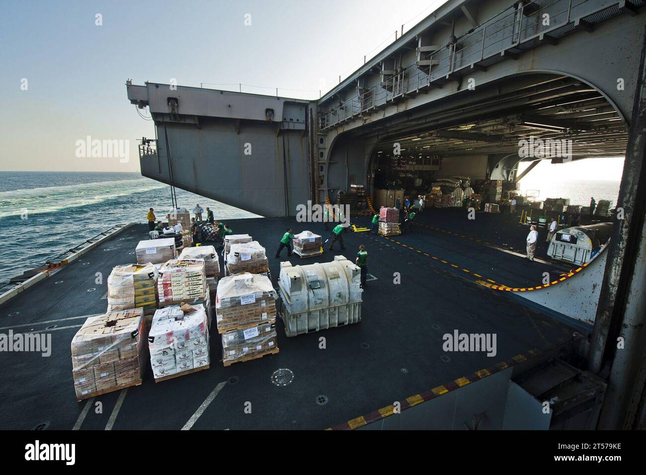 US Navy Sailors move cargo from an aircraft elevator during a ...