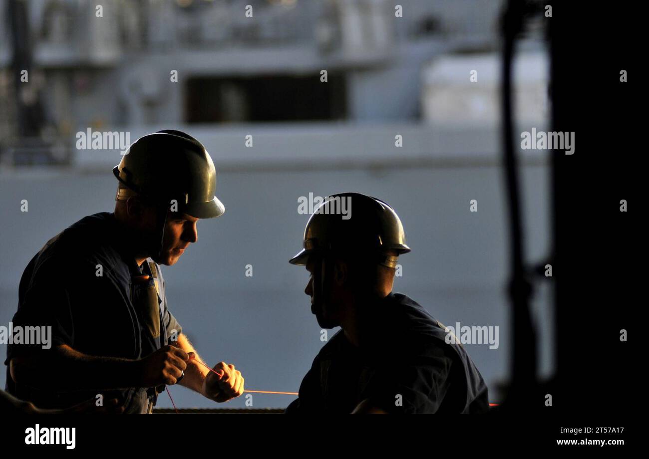 US Navy Sailors pull in the messenger line in the hangar bay aboard the ...
