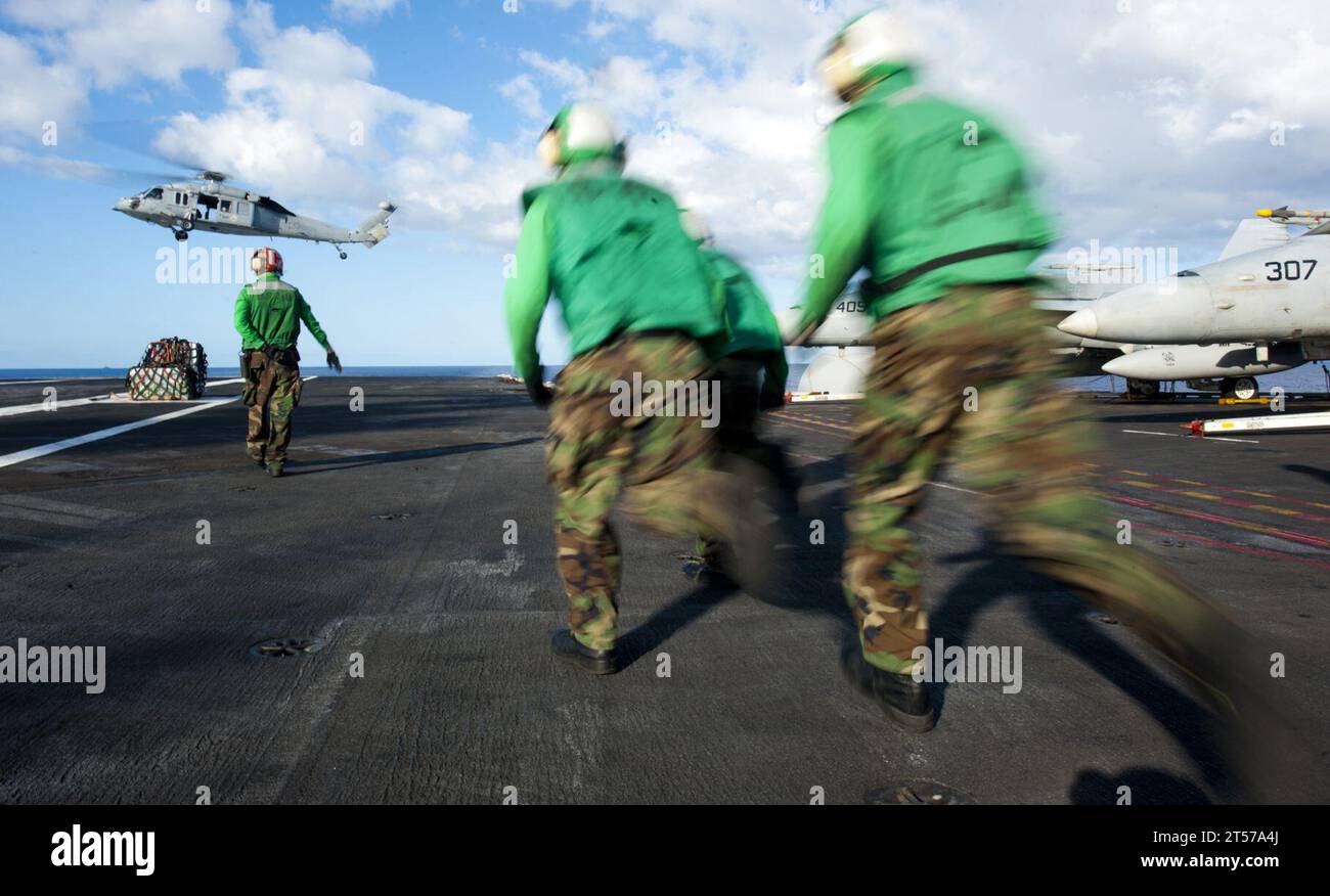 US Navy Sailors run to move cargo on the flight deck during a vertical ...