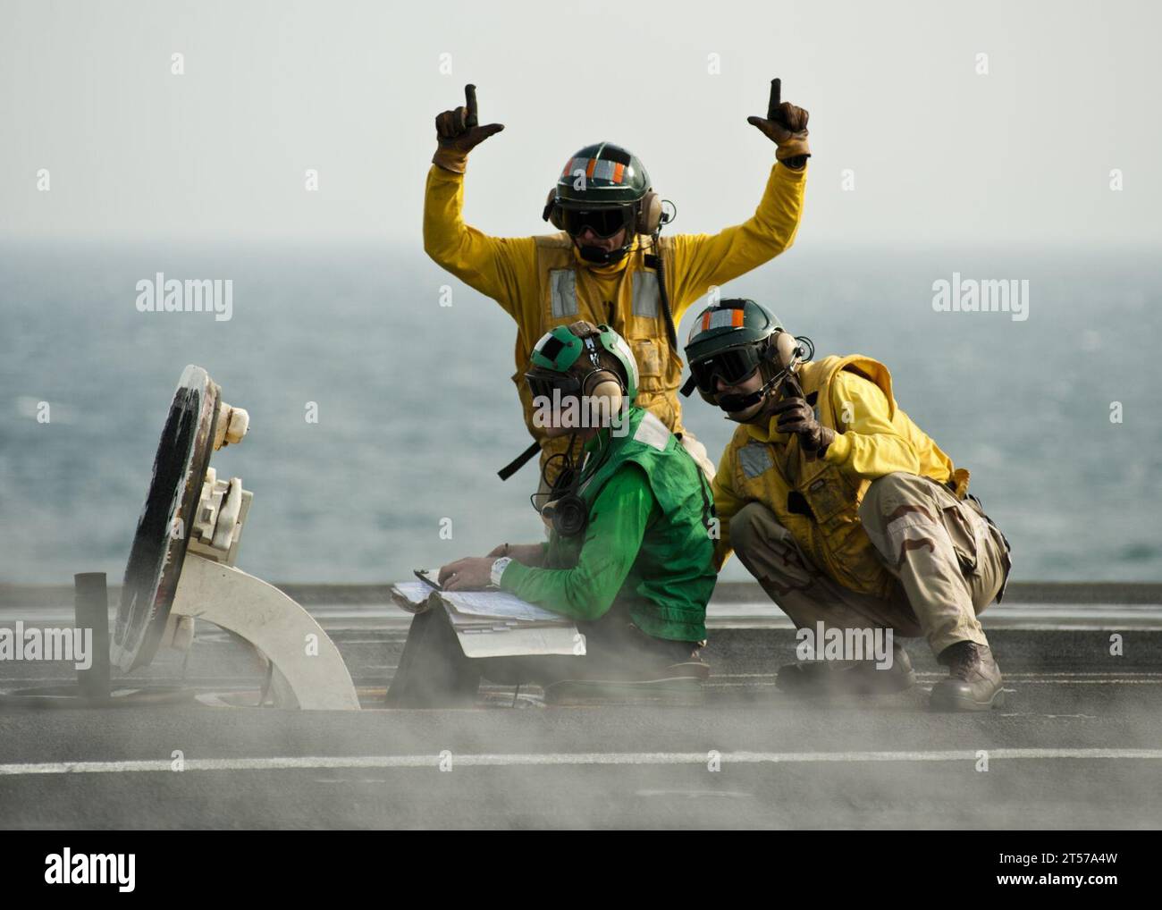 US Navy Sailors signal a safety warning as ordnance is armed on an F18F ...