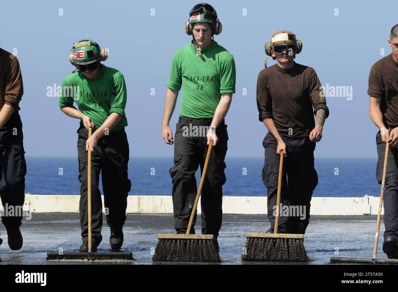 US Navy Sailors scrub the flight deck of the Nimitz-class aircraft ...