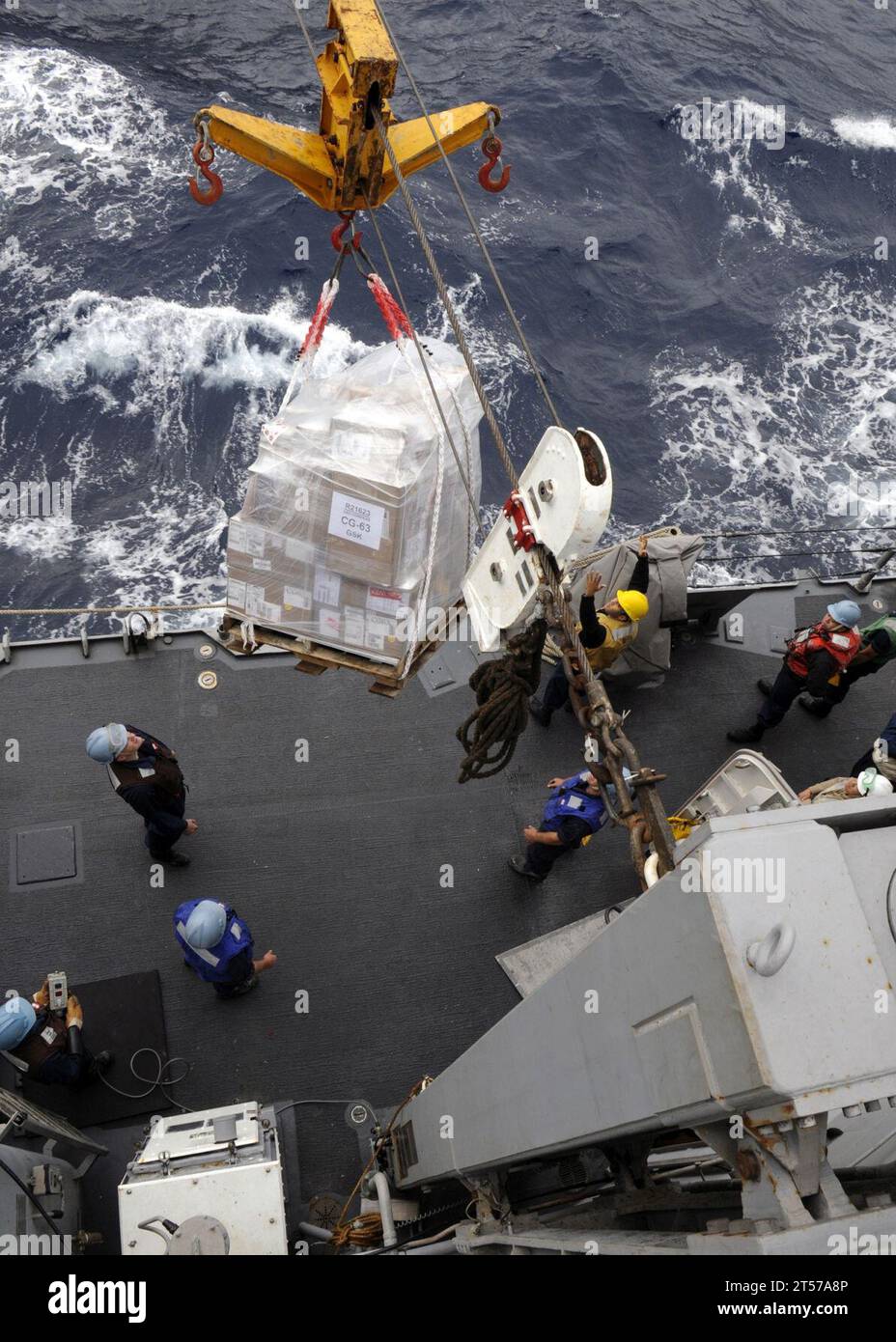 US Navy Sailors stand by as a pallet of spare parts is transferred to ...