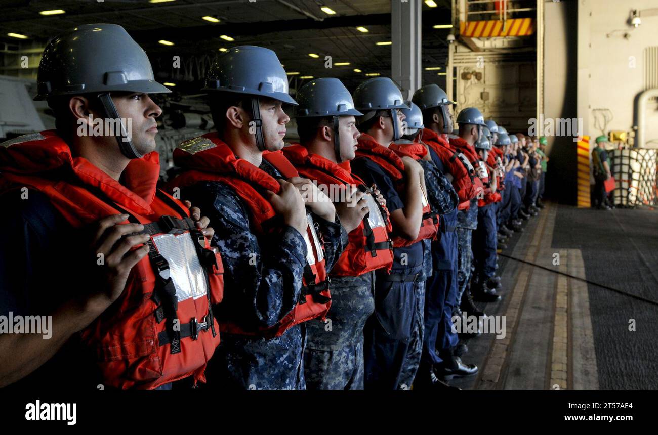 US Navy Sailors wait to handle lines in the hangar bay aboard the ...