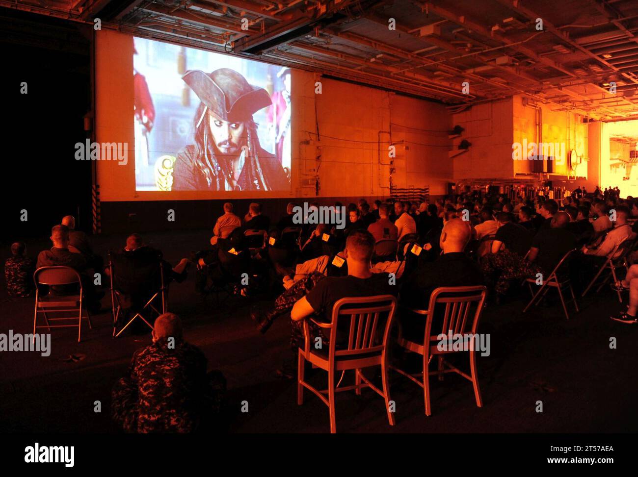 US Navy Sailors watch a movie during movie night in the hangar bay ...