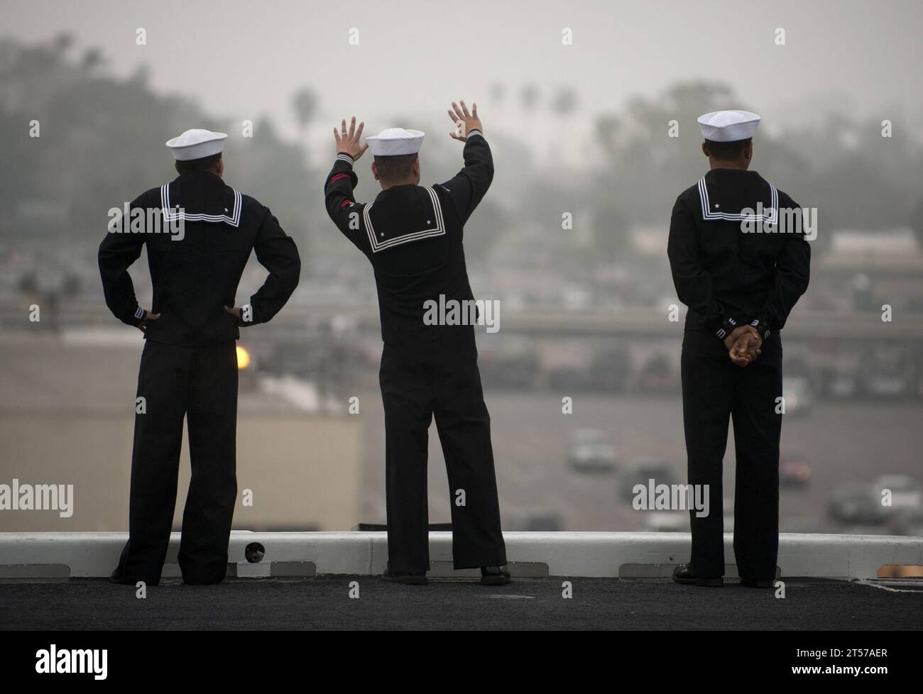US Navy Sailors wave goodbye to loved ones on the pier while manning ...