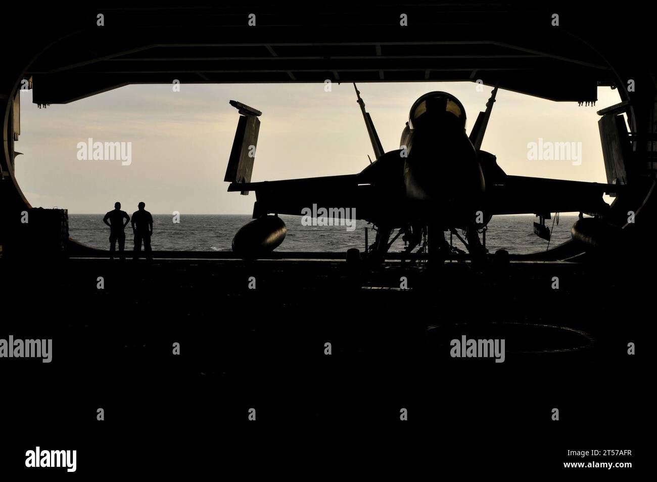 US Navy Sailors watch the sunset from the hangar bay aboard the Nimitz ...