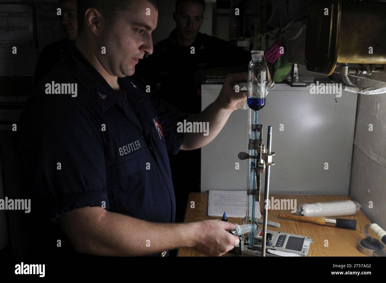 US Navy Sailors uses a titration rig to measure volumes of liquid while ...
