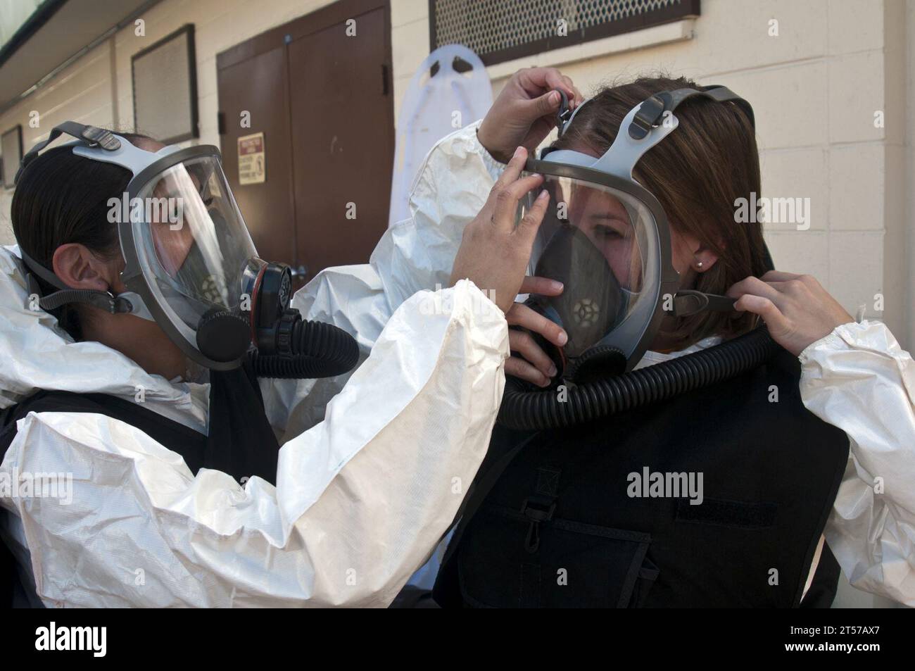 US Navy Service members help one another put on decontamination suits ...