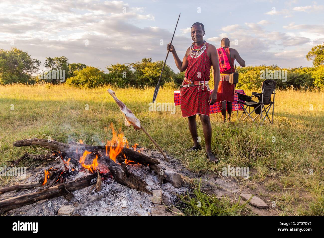 MASAI MARA, KENYA - FEBRUARY 20, 2020: Masai men roasting a goat leg ...