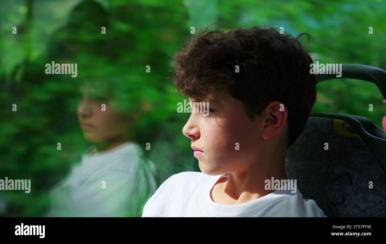 close-up of contemplative preteen boy aboard bus, engrossed in scenic ...