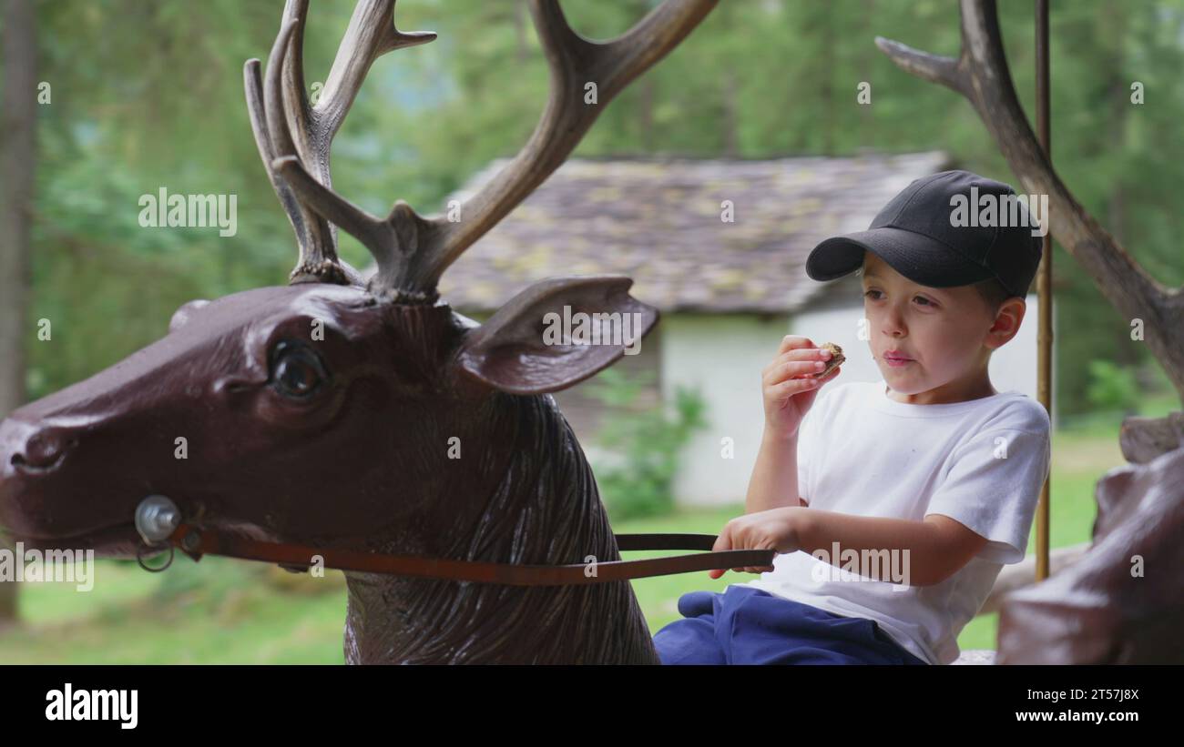 Happy child riding carousel on top of deer circus toy. Little boy ...