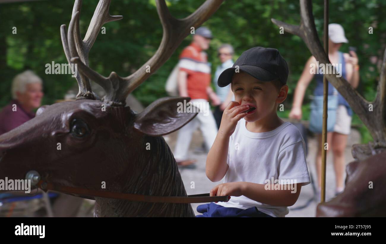 Happy child riding carousel on top of deer circus toy. Little boy ...