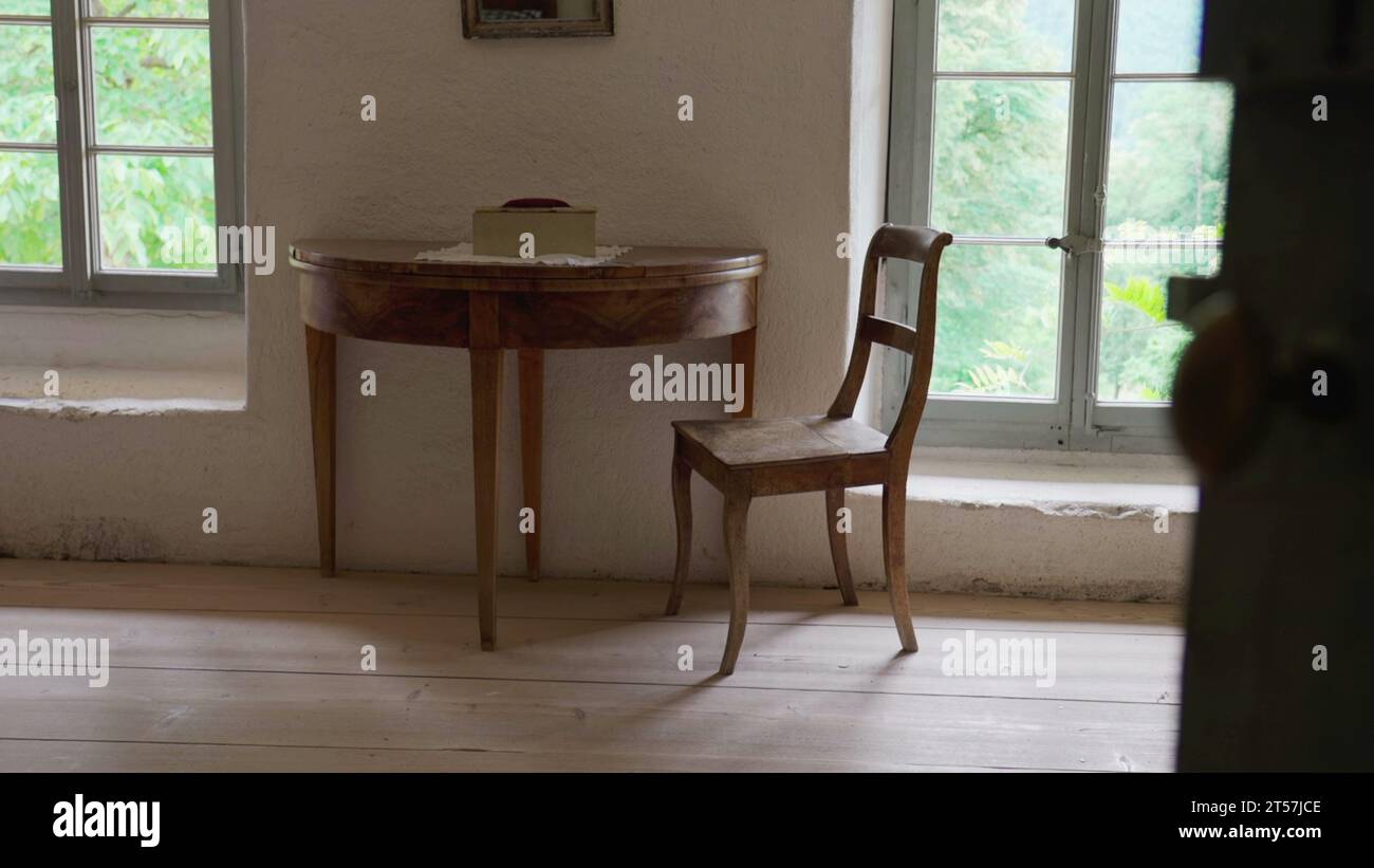Rustic farmhouse setting, antique wooden table and chair by window in ...