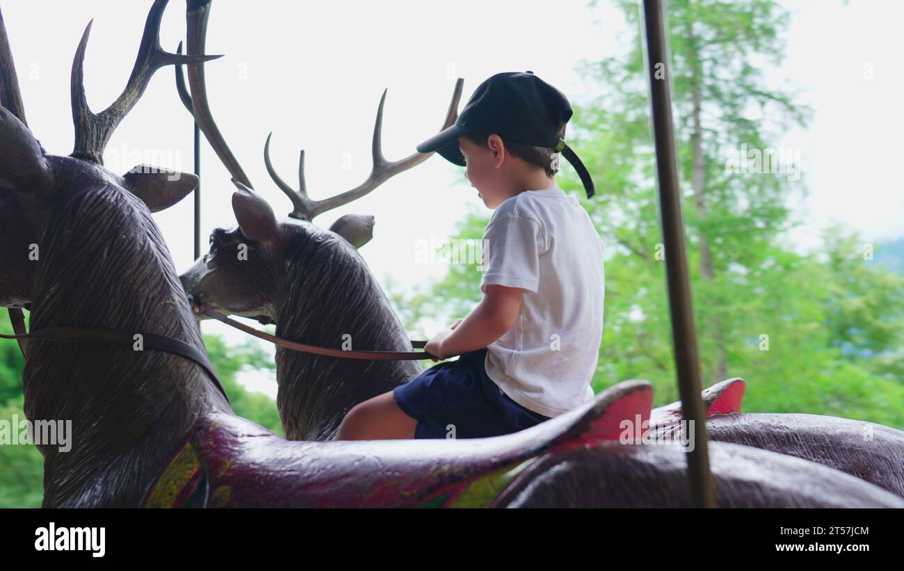 Happy small boy riding merry-go-round, rides carousel. Excited child ...
