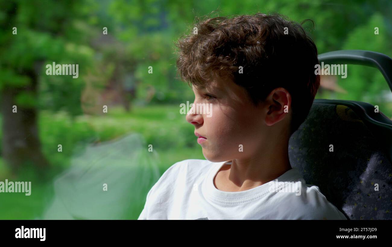 reflective young boy on bus, lost in distant gaze. Youthful traveler ...