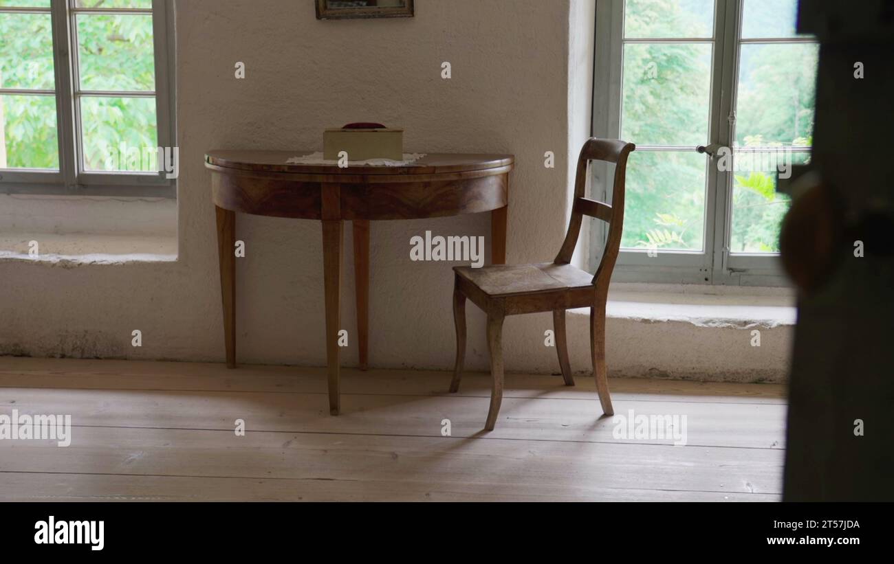 Rustic farmhouse setting, antique wooden table and chair by window in ...