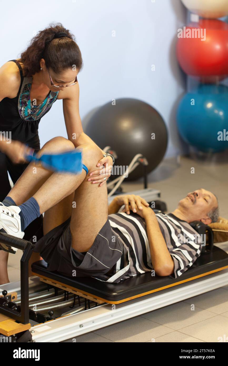 sick old man doing therapy recovery on a pilates machine with a female ...