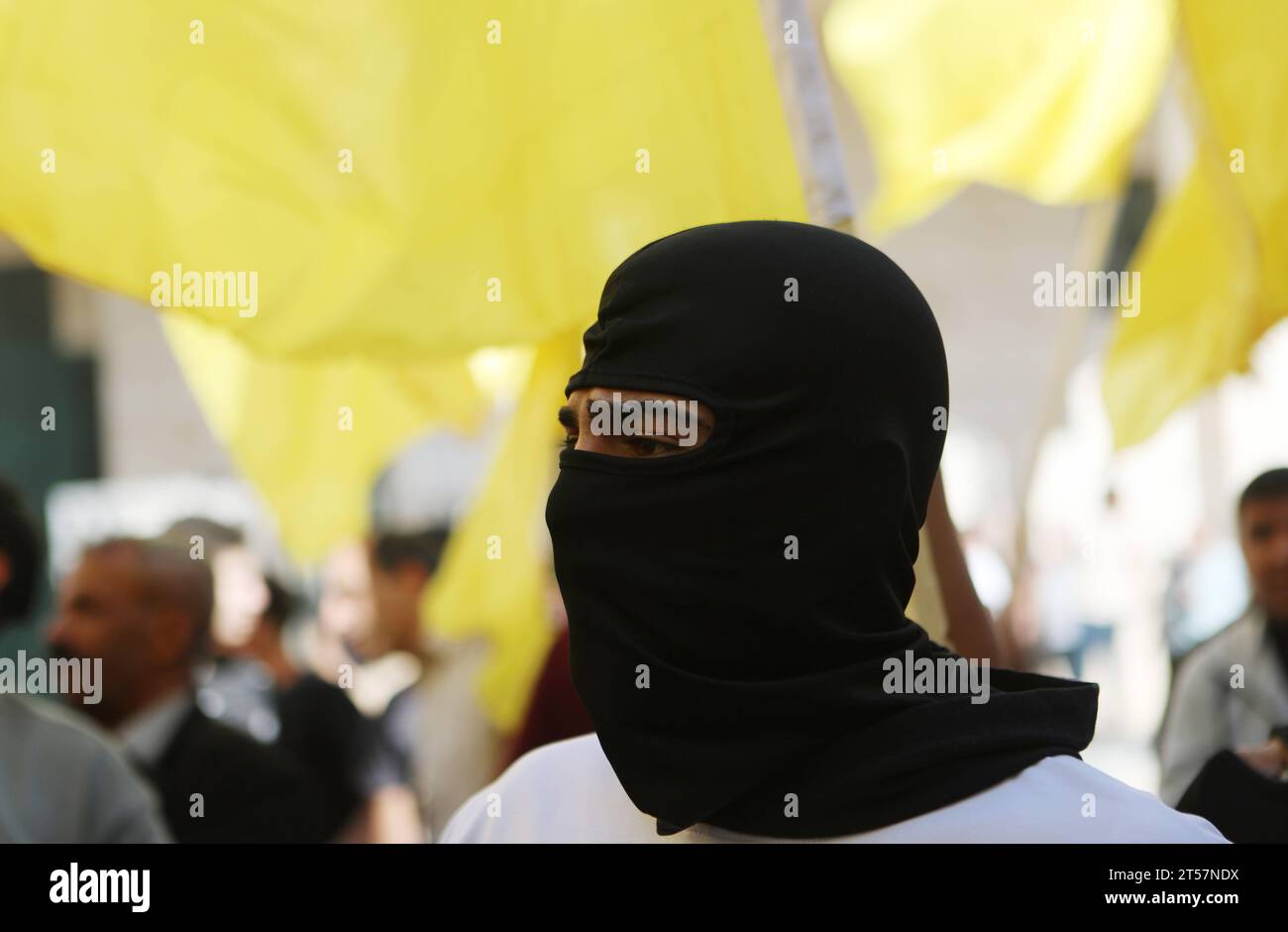 Palestinians holds up the yellow Fatah flag and the green Hamas flag ...
