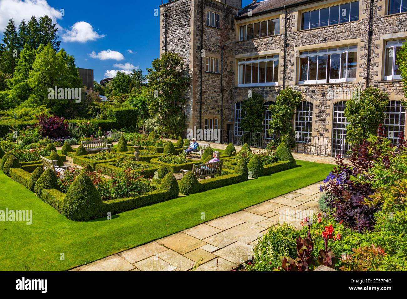 Two visitors admiring the colourful borders and topiary hedges in the ...