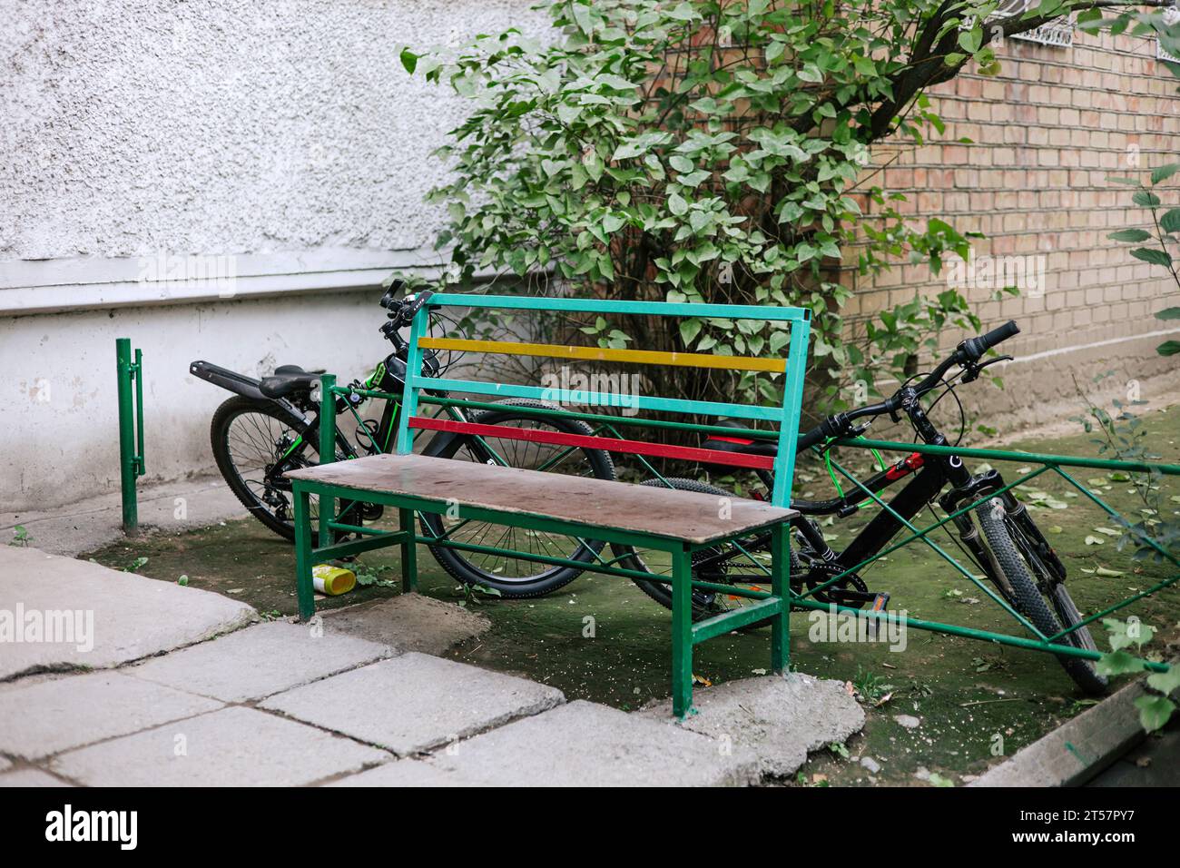 Two bicycles left unattended in the yard near a colorful bench ...
