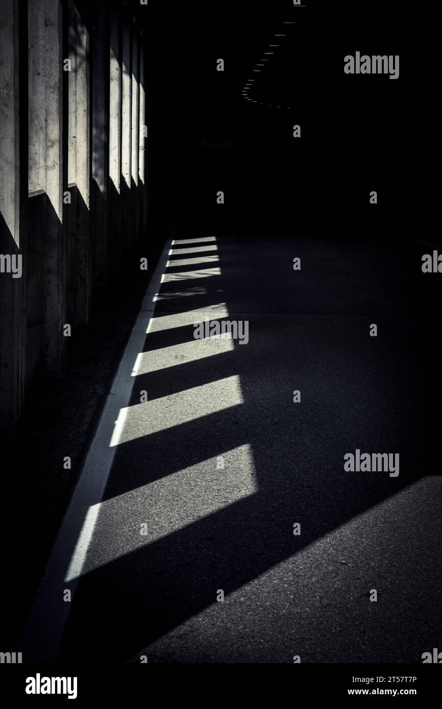 Shadows and light play on the road surface of a mountain tunnel in the ...