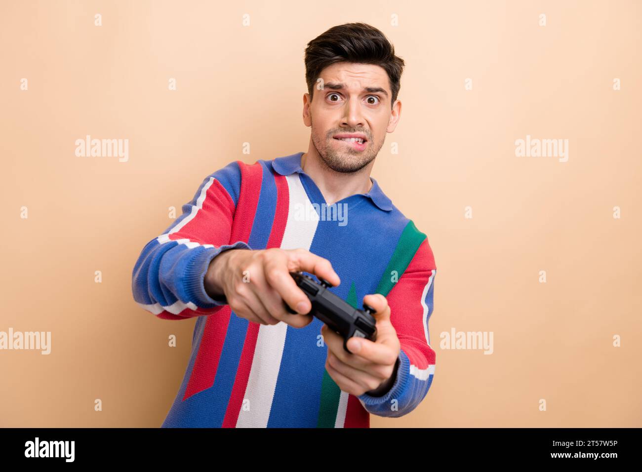 Portrait of worried young person biting lips arms hold controller play ...