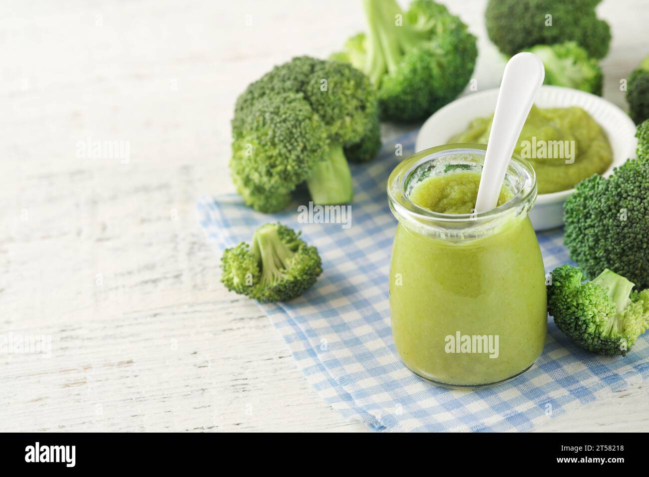 Green broccoli baby food in white bowl and jar on table. Green baby ...
