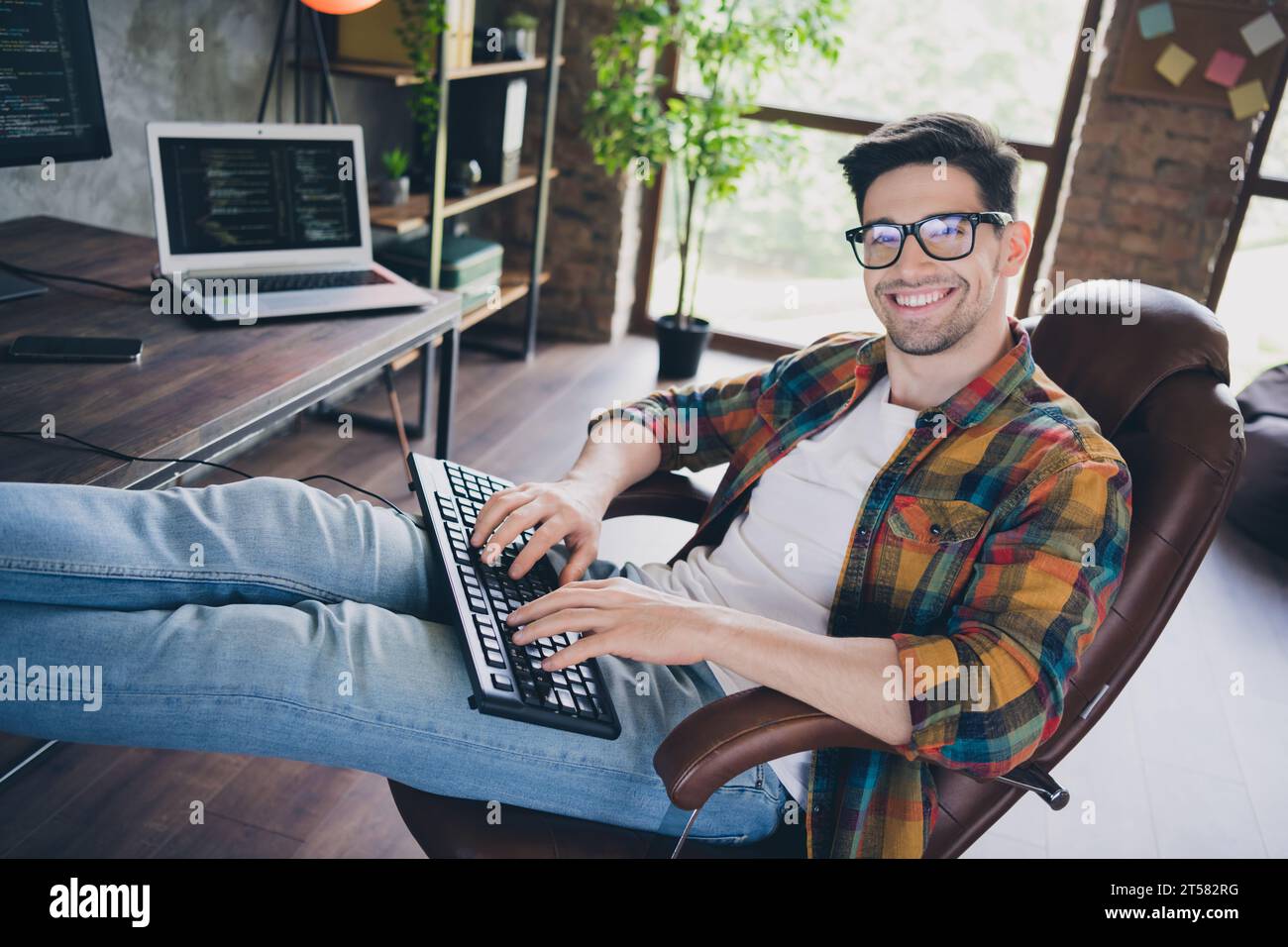 Profile photo of smart positive web designer guy sitting chair legs desk keyboard typing ...