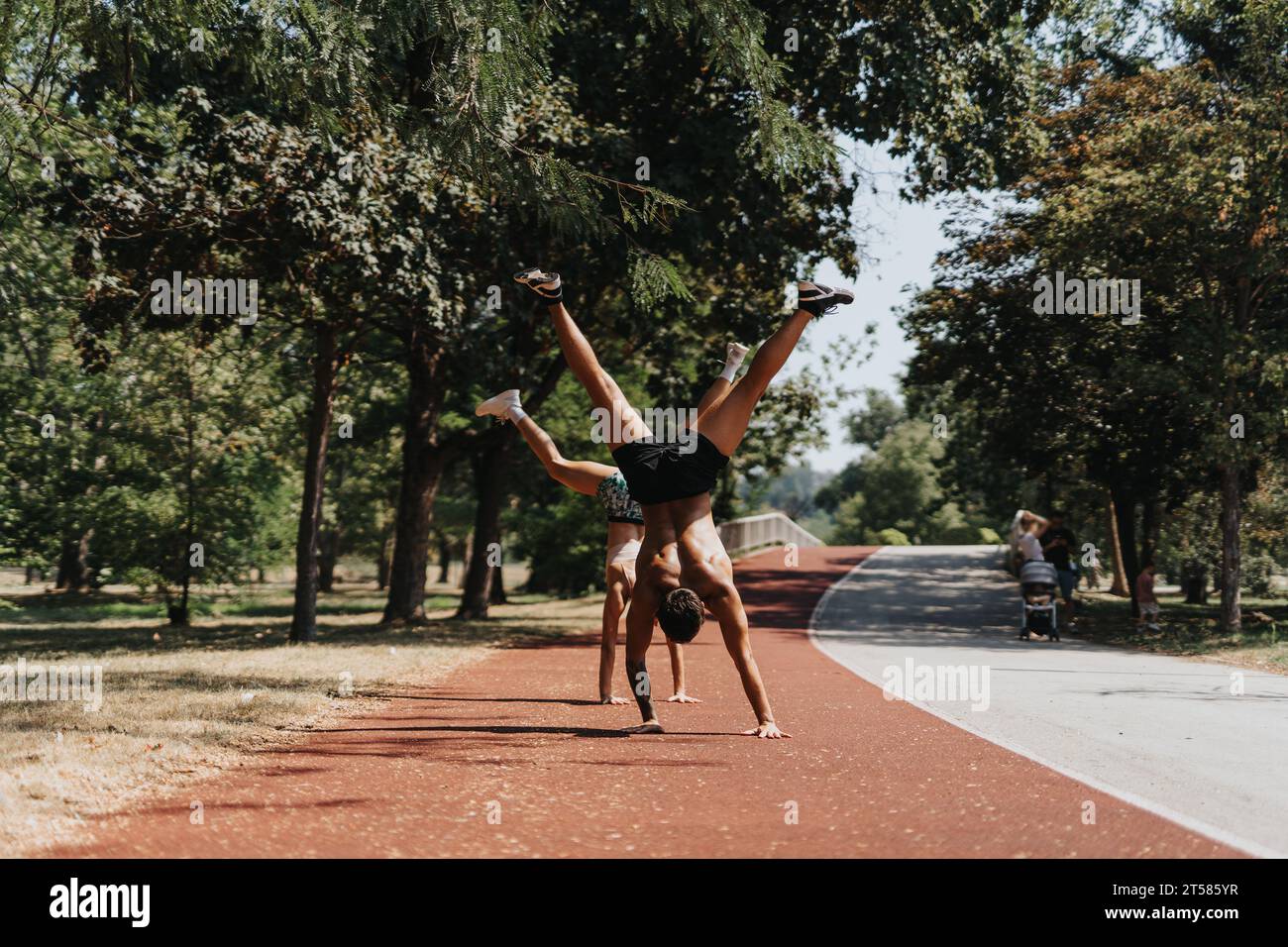 Couple doing cartwheel on a race track in the park Stock Photo - Alamy