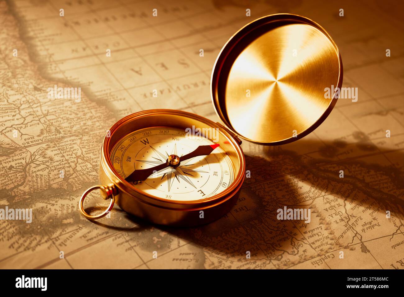 close-up view of a vintage gold compass lying on an old, weathered map ...