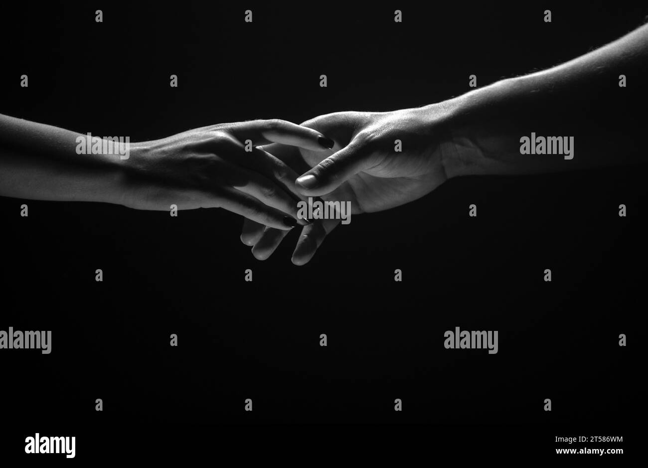 Two hands stretch each other, black background. Couple in love holding ...