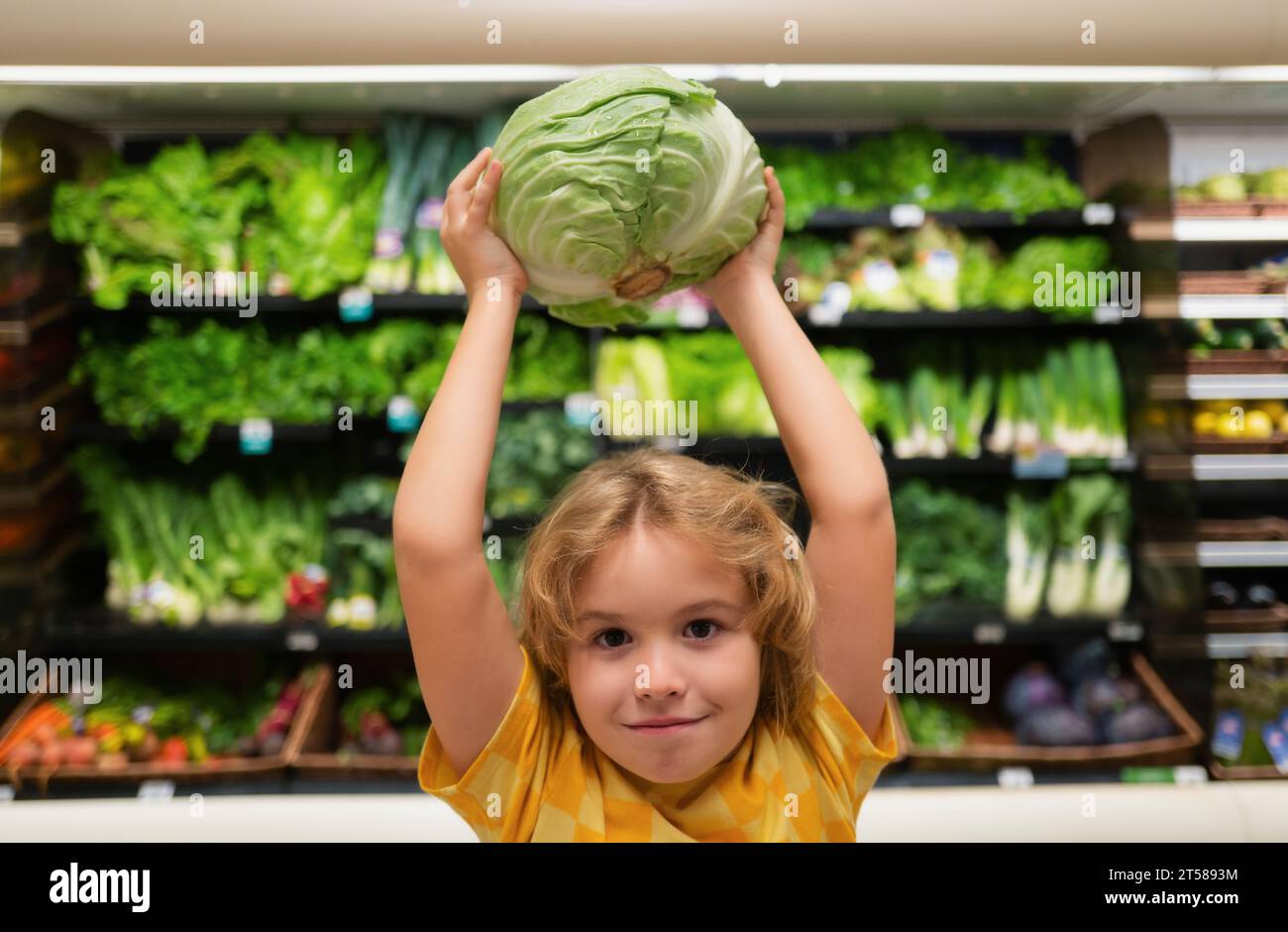 Child with cabbage. Kid in a food store or a supermarket. Little kid ...