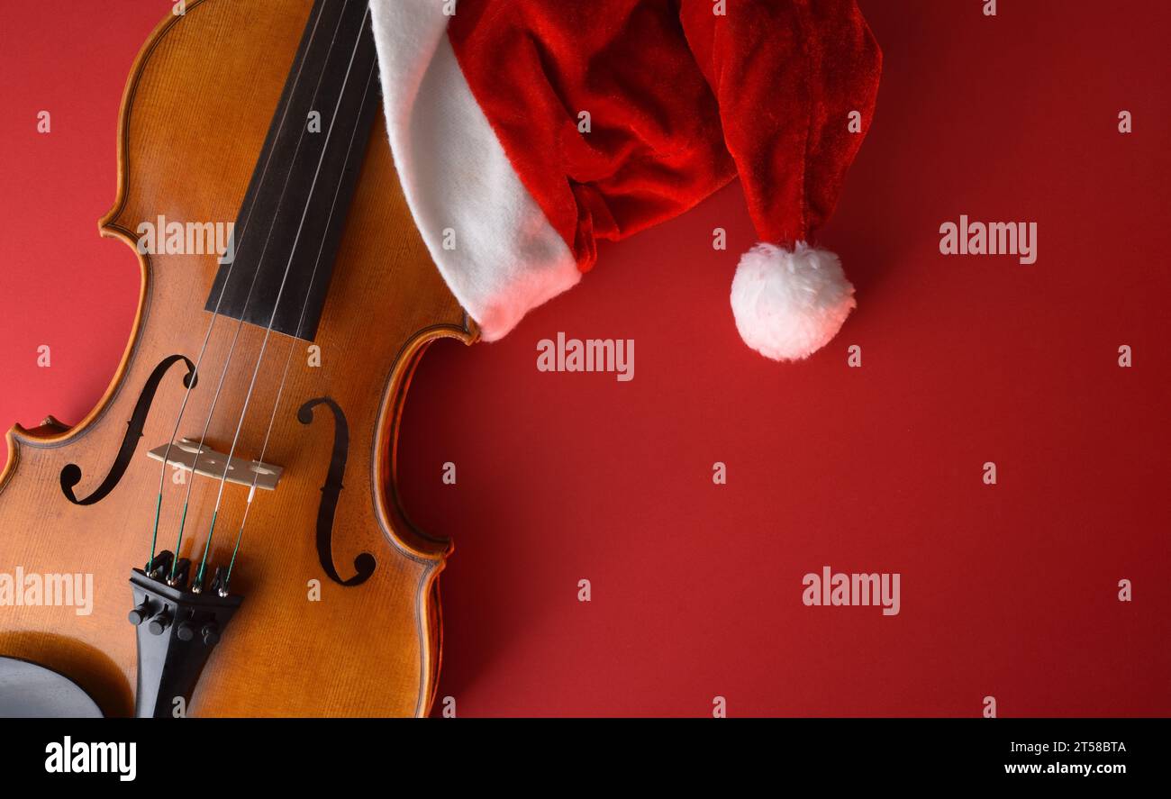 Detail of violin body with Santa hat on the left on a red background ...
