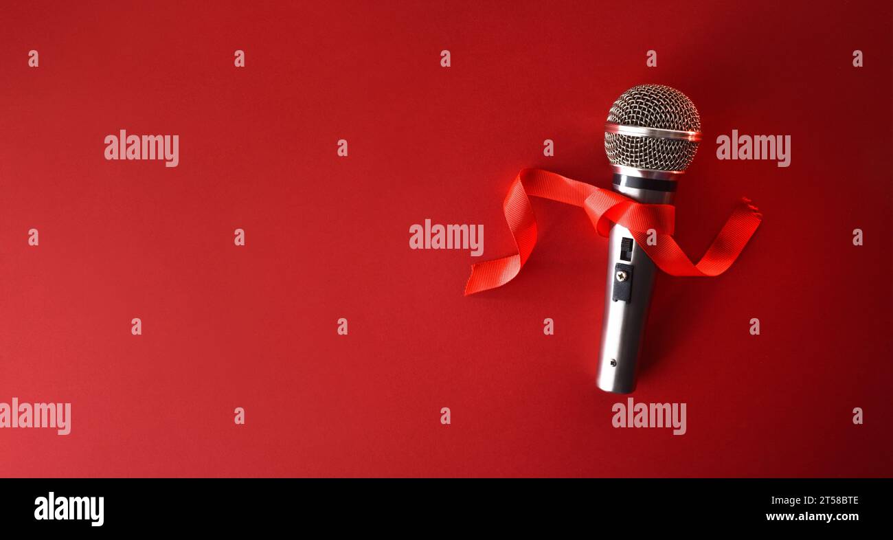 Metallic stage microphone with red bow isolated on red background. Top ...