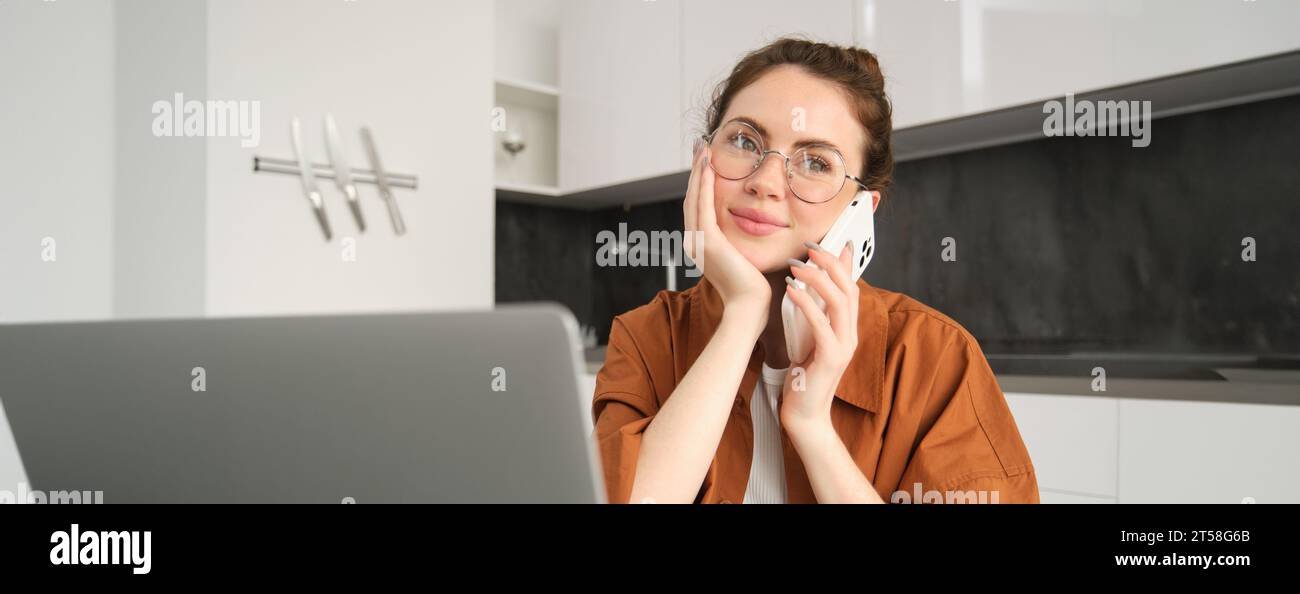 Portrait of beautiful smiling woman working from home, talking on ...