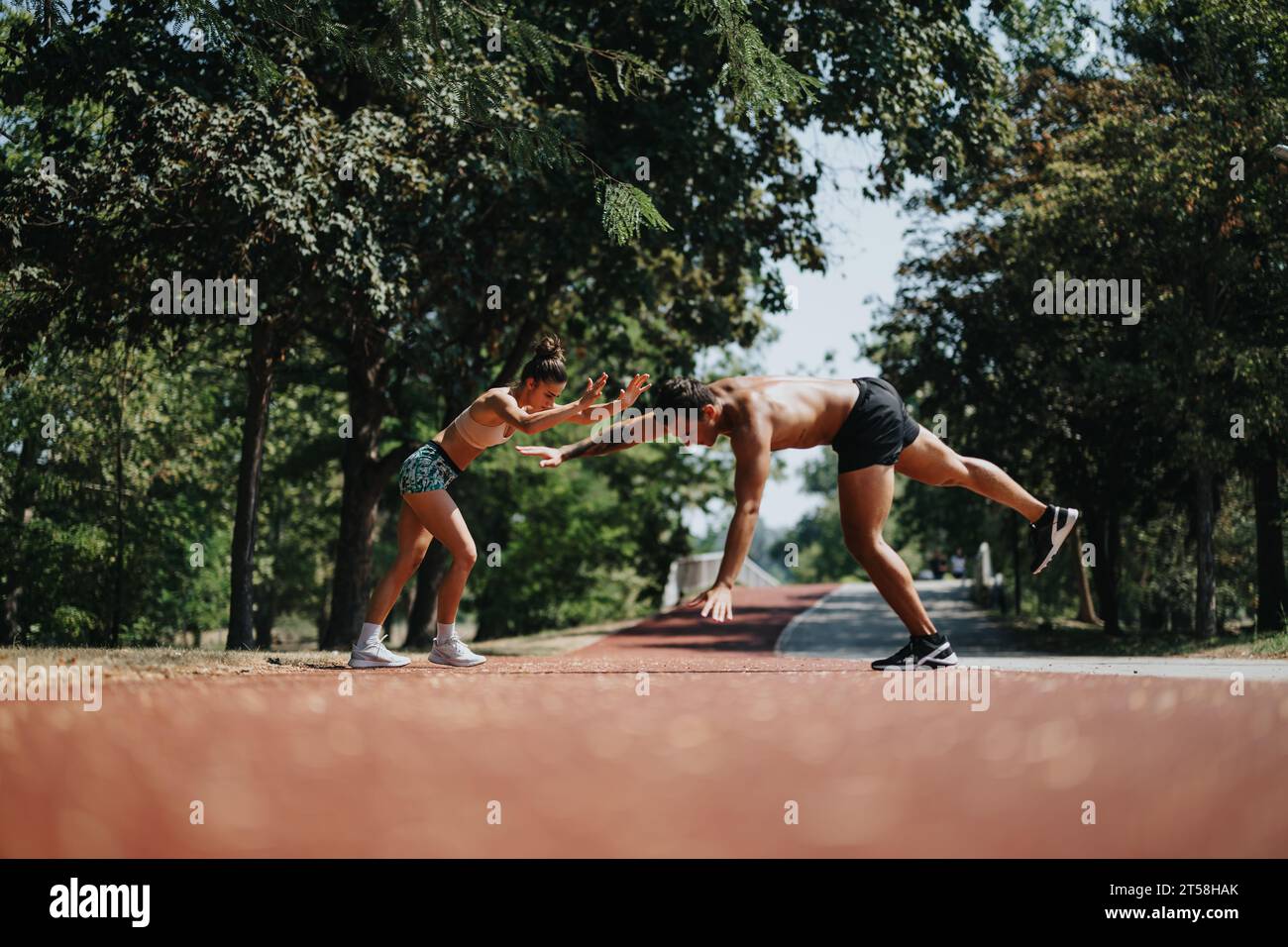 Fit couple of athletes performing cartwheels in a sunny park, inspiring ...