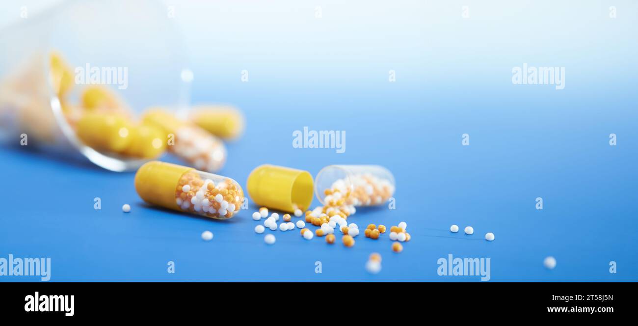 Split-open yellow capsule on blue gradient background. Copyspace, place ...