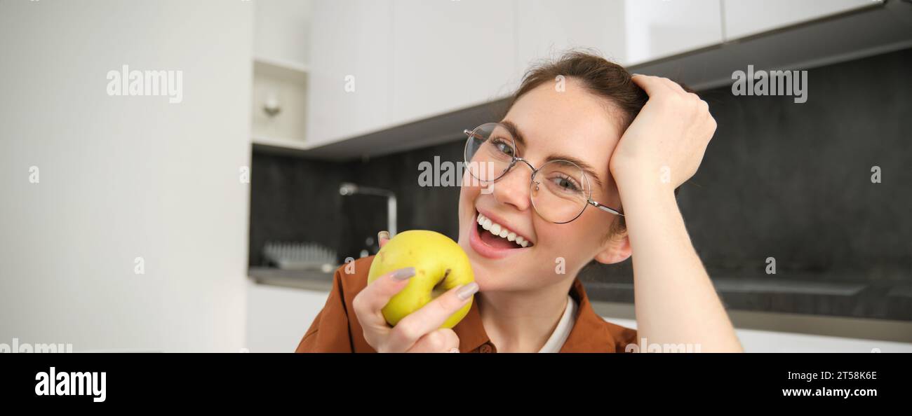 Close up portrait of happy, stylish young woman at home, biting an ...