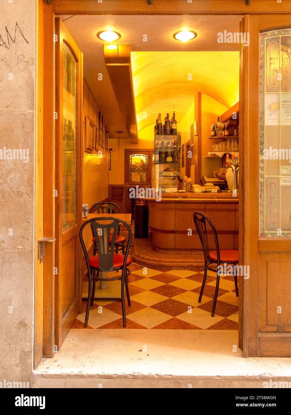 The interior of a Venice bar photographed through the door. We see ...