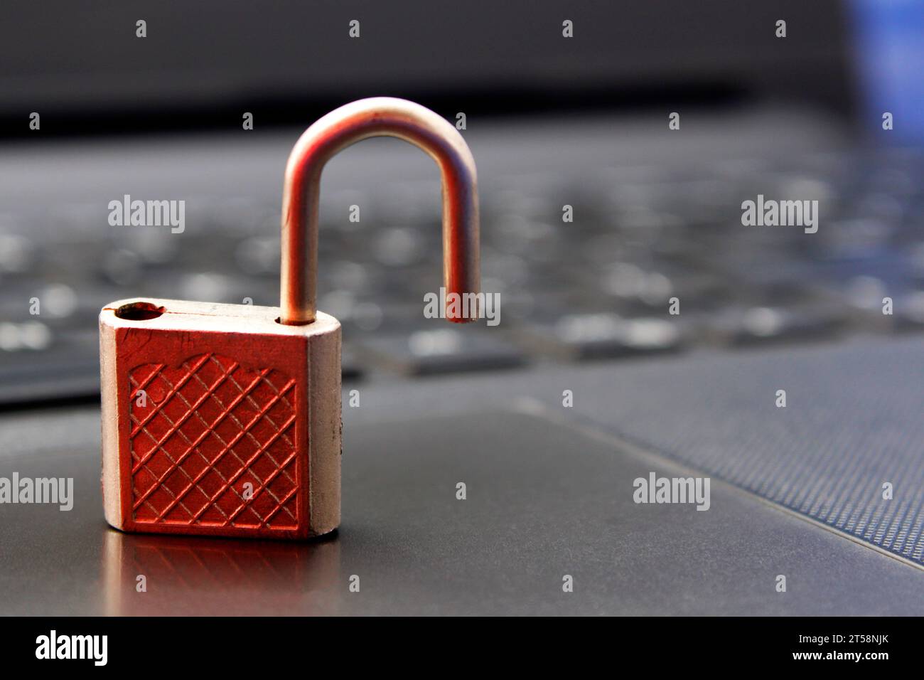Open padlock with red light reflection indicating security alert on computer keyboard background ...