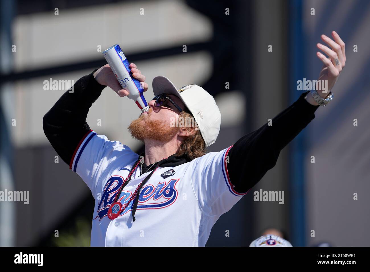 Texas Rangers' Jon Gray drinks a beer as he rides on a the back of a ...