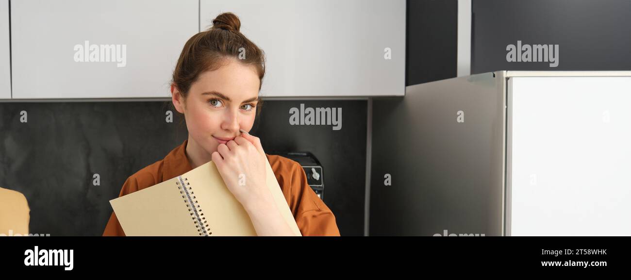 Portrait of young modern woman, 25 years old, standing in the kitchen ...