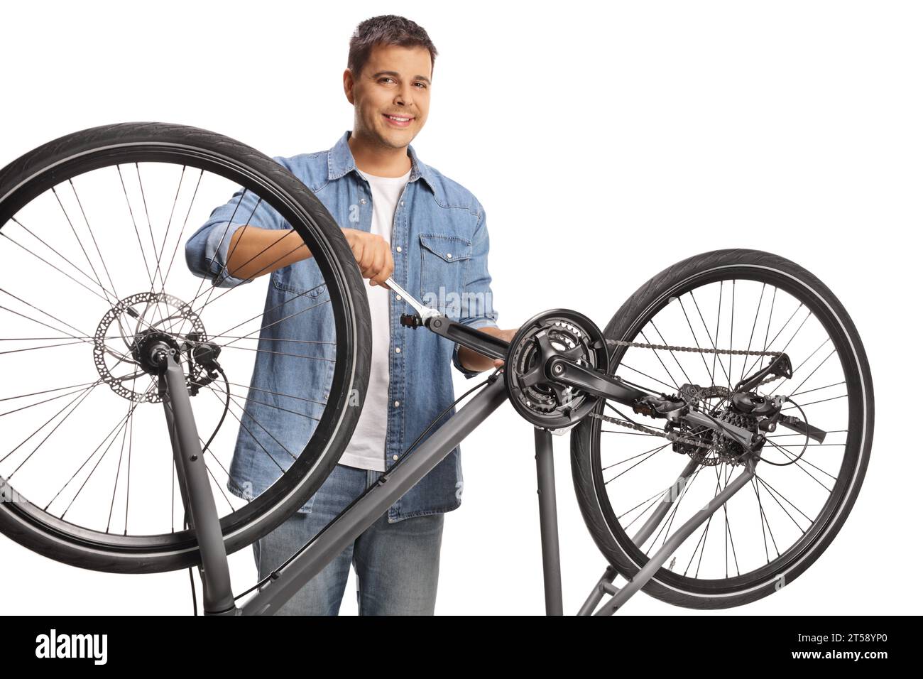 Young man fixing a bicycle with a pedal wrench isolated on white ...