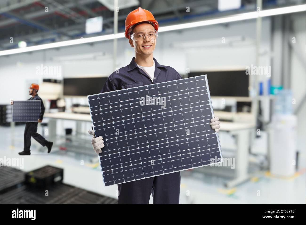 Workers inside a factory carrying solar panels, manufacturing industry ...