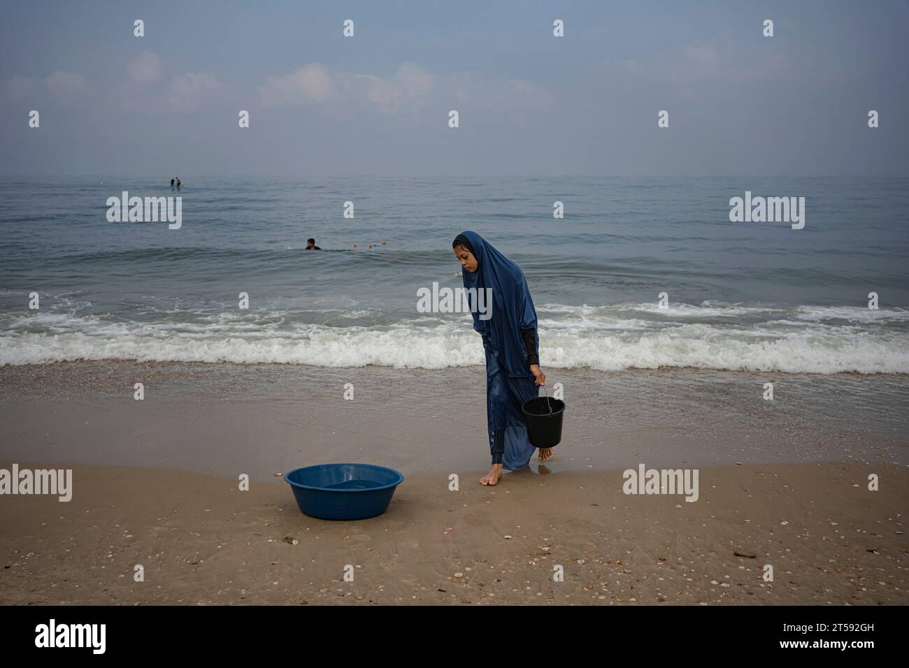 A Palestinian woman collects seawater to wash clothes at the beach in ...