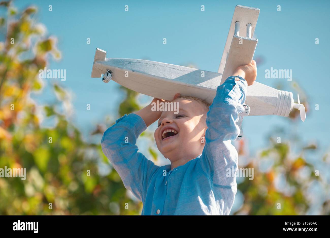 Kid dreaming and plays with a toy plane in the park. Dreams of travel ...
