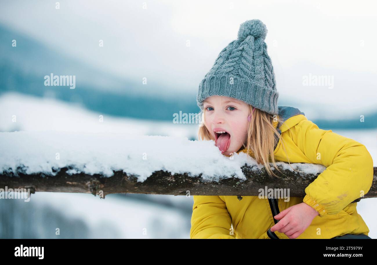 Cute little winter girl eating snow outdoor. Excited christmas kids ...