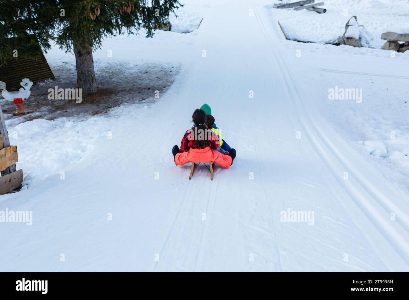 group of children in bright winter clothes riding one wooden sled going ...