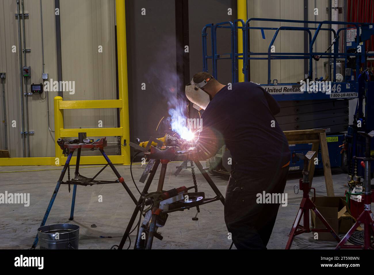 Worker welding piping used in a cold-storage (industrial refrigeration ...